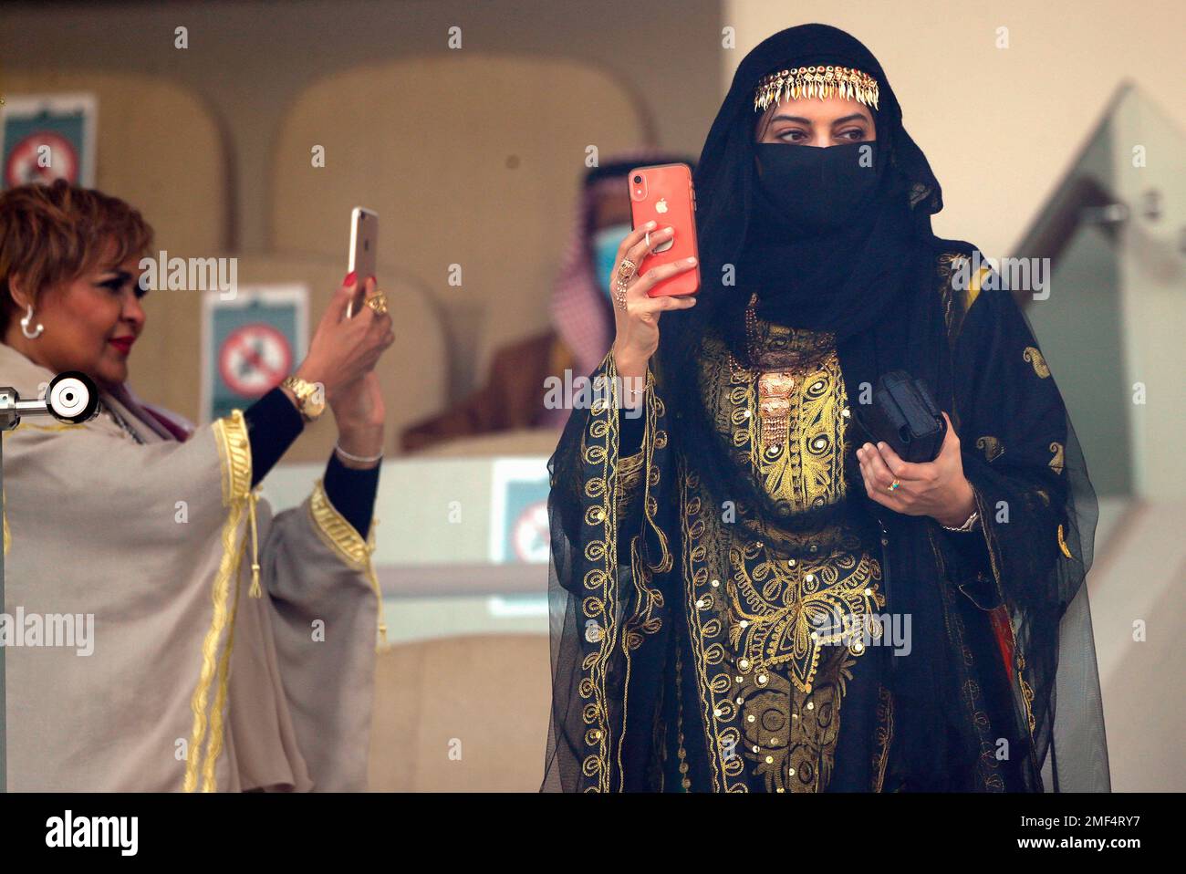 Saudi women, wearing traditional costumes, watch and film the horse ...