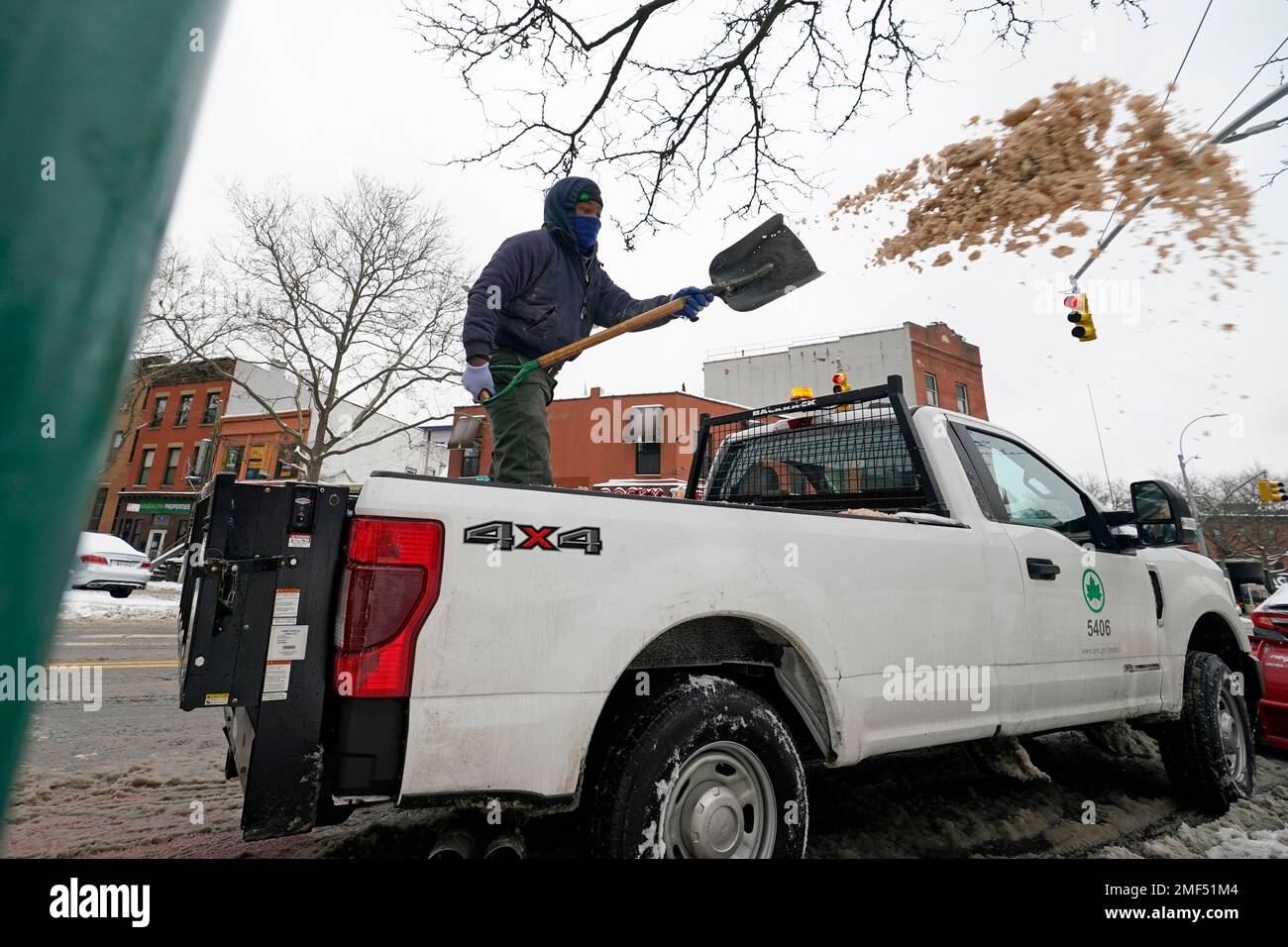 A city parks worker throws salt from a truck onto a bus stop after ...