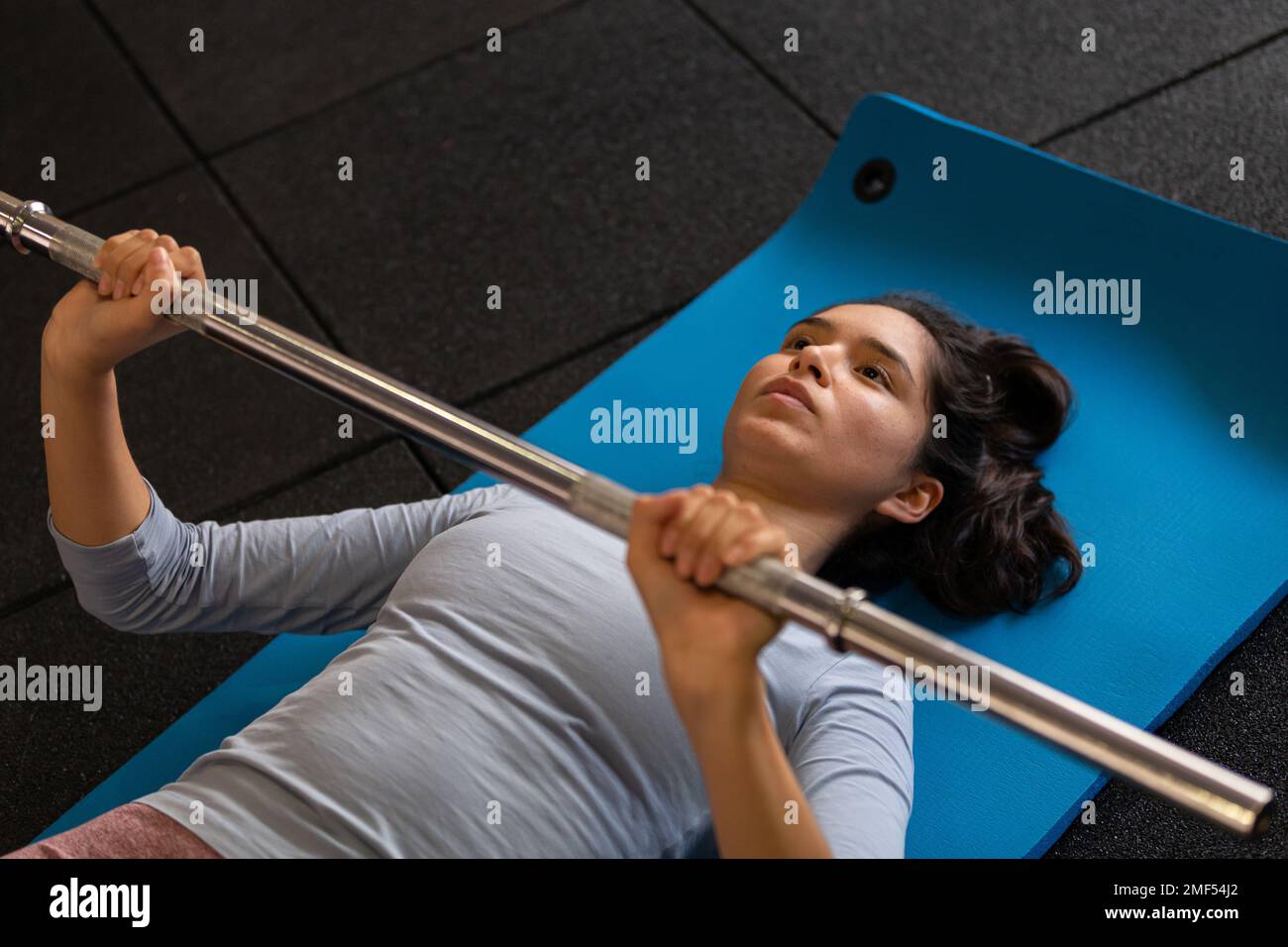 Beautiful sportswoman doing exercises indoors in gym, lying on mat ...