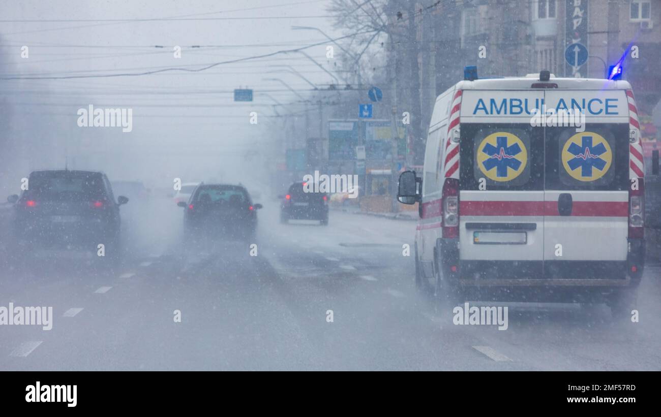An ambulance car is driving along the city street at high speed. Rain ...