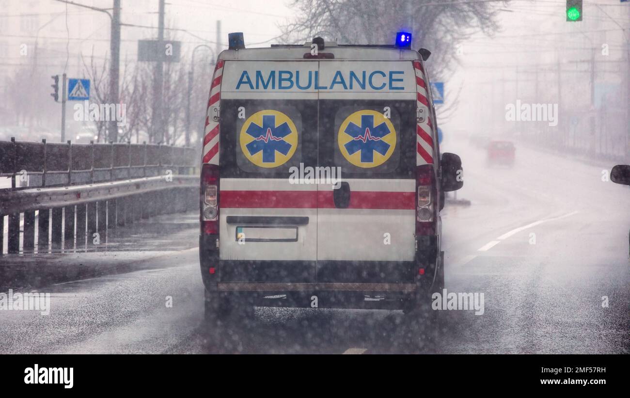 An ambulance car is driving along the city street at high speed. Rain ...