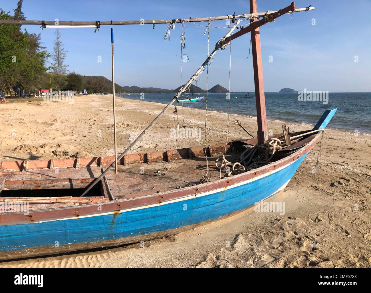 On the beach of Dolphin Bay, a traditional fishing boat sits on the the ...