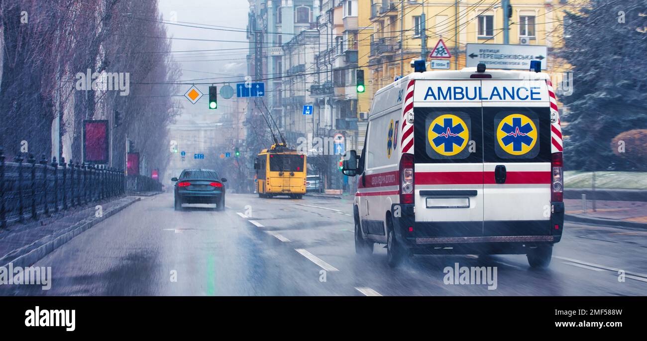 An ambulance car is driving along the city street at high speed. Rain ...