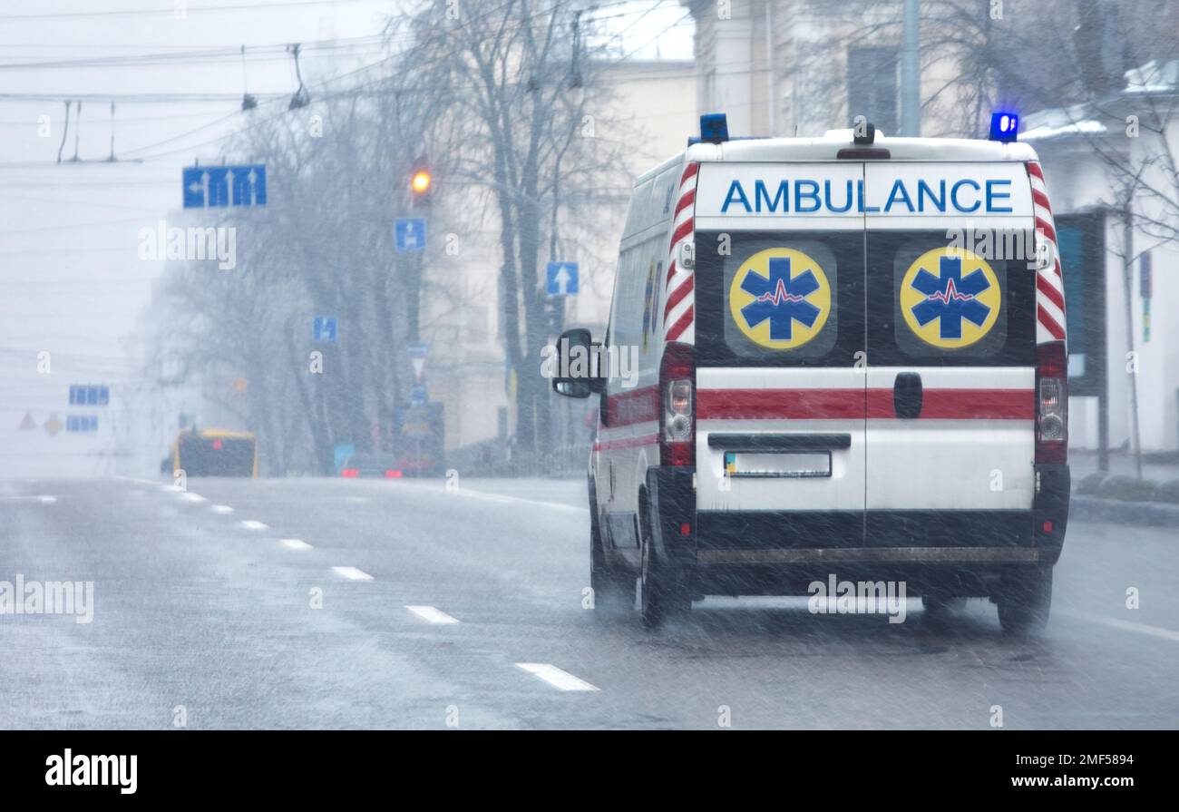 An ambulance car is driving along the city street at high speed. Rain ...