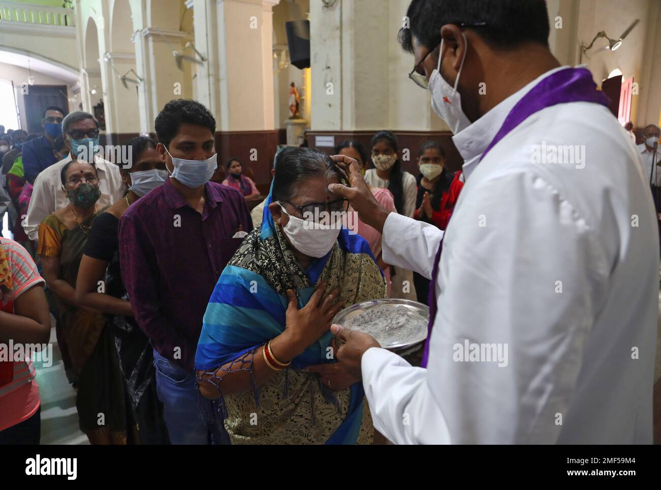 A Catholic priest marks the forehead of a devotee with the symbol of a ...