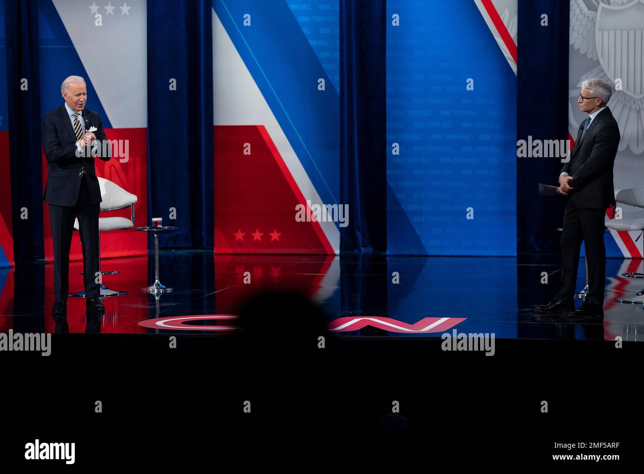 Anderson Cooper listens as President Joe Biden speaks during a ...