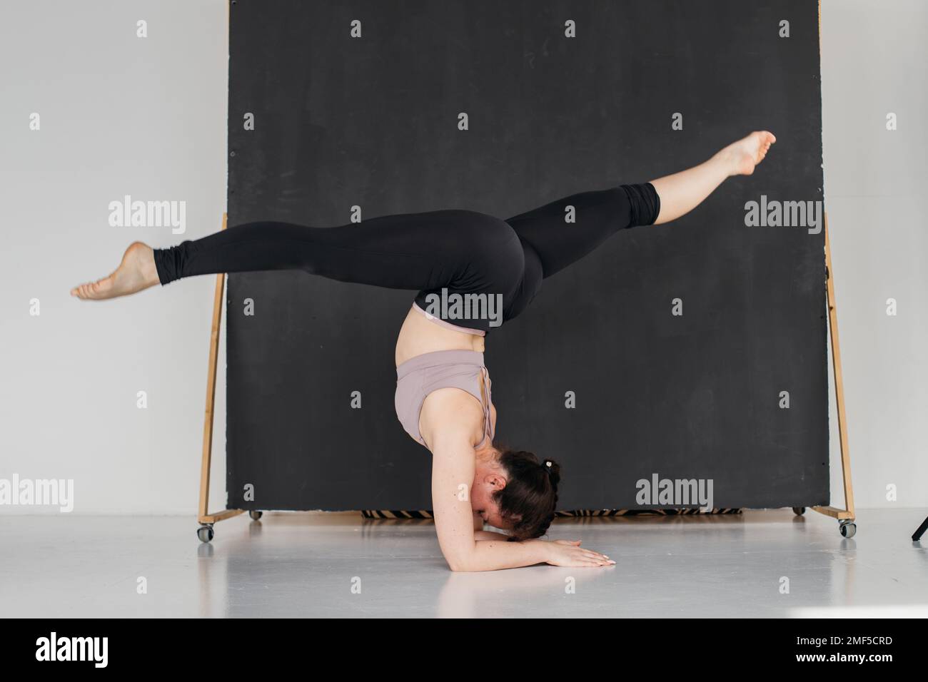 Young professional gymnast woman standing on splits. Pretty brunette ...