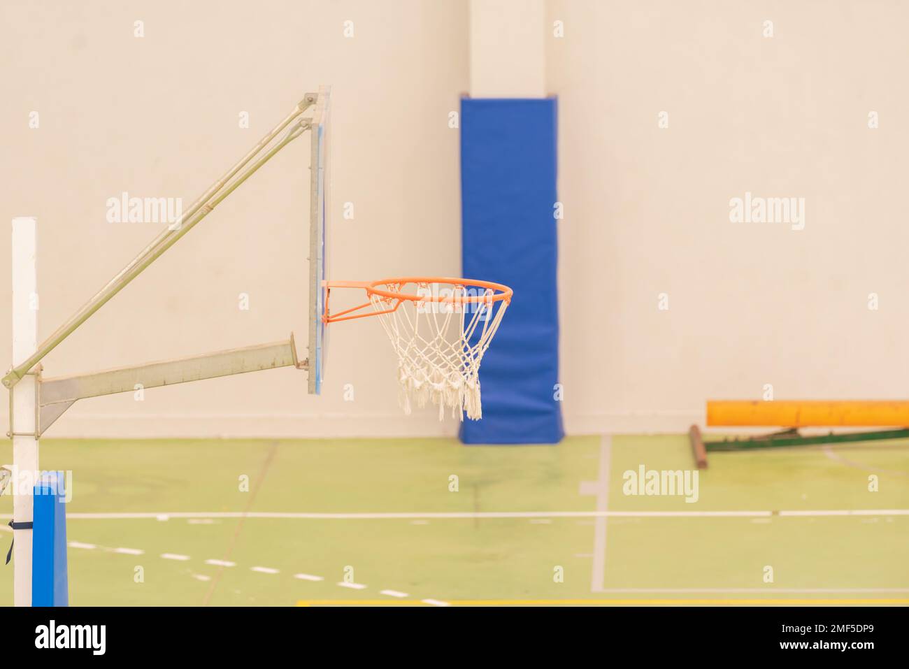 side view of a basketball entering a mini-basketball basket on a court ...