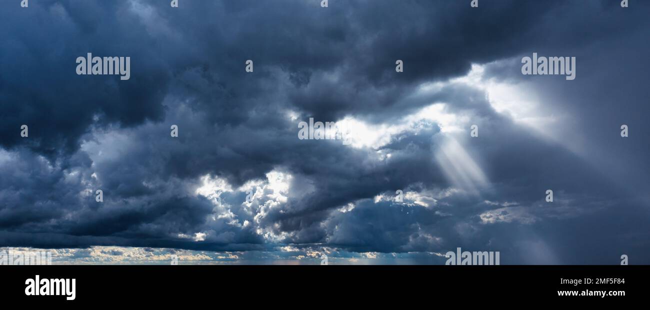 The beginning of a powerful thunderstorm. Dark rain clouds and sun rays ...