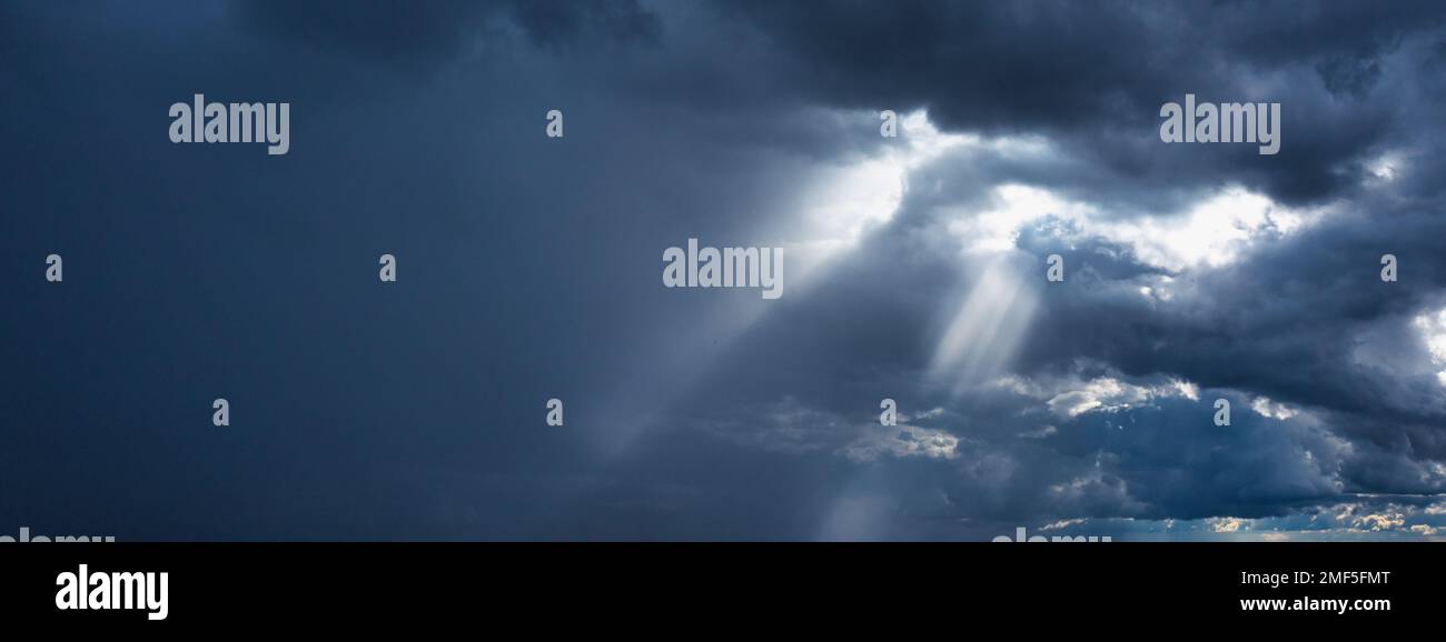 The beginning of a powerful thunderstorm. Dark rain clouds and sun rays ...