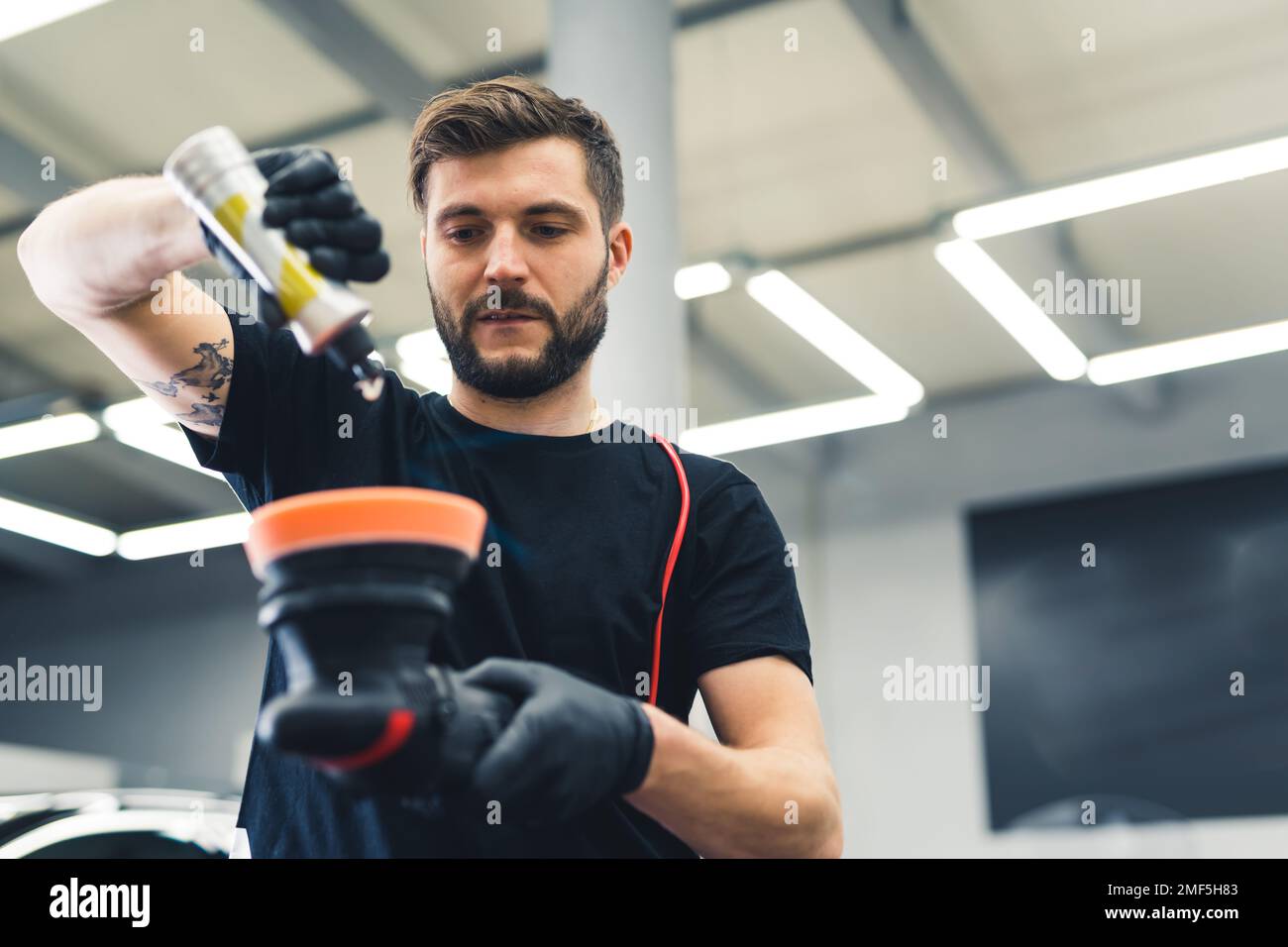 Caucasian man wearing black gloves preparing his professional buffer ...