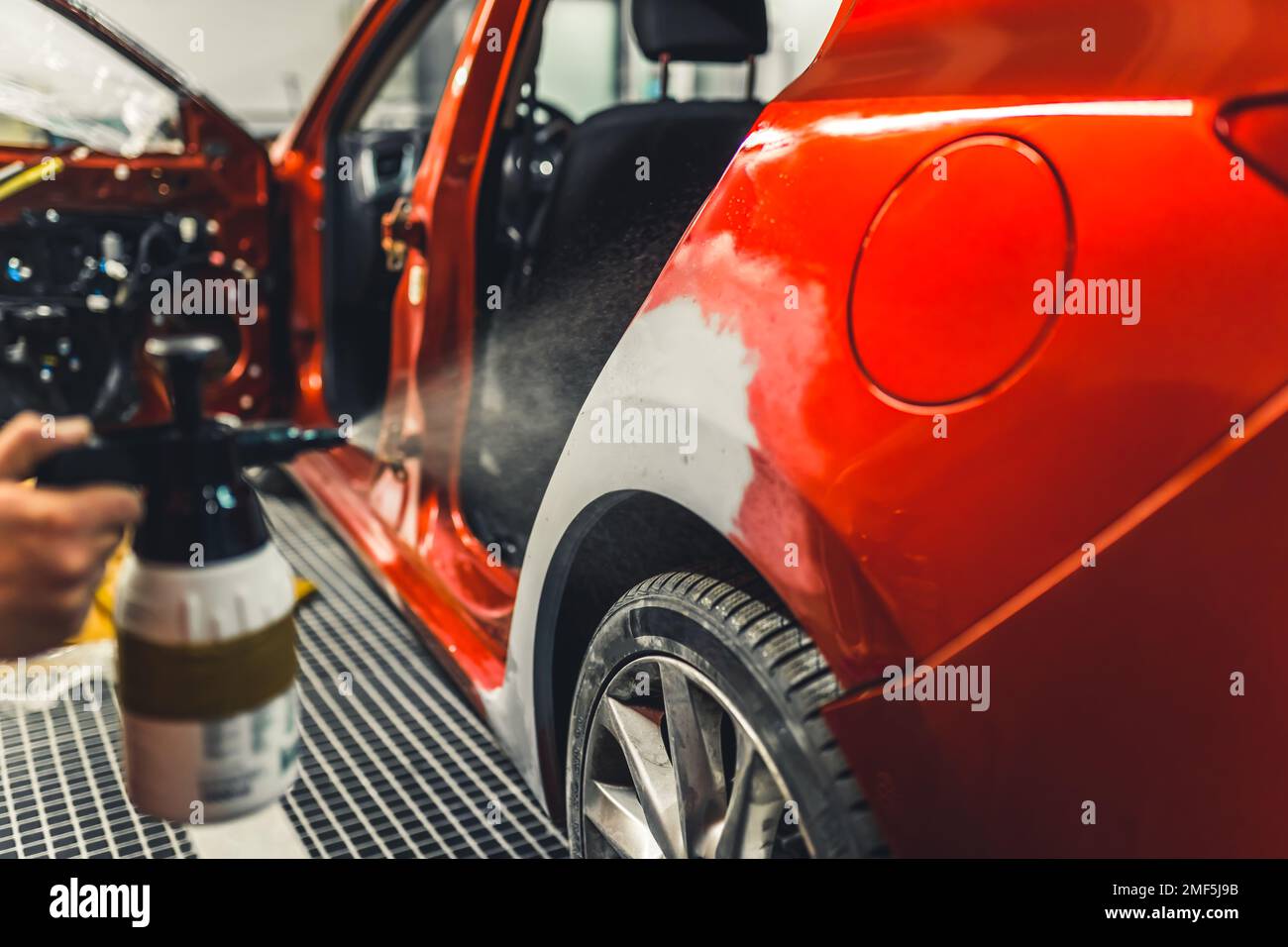 Unrecognisable person removing dent from body of red car using putty ...