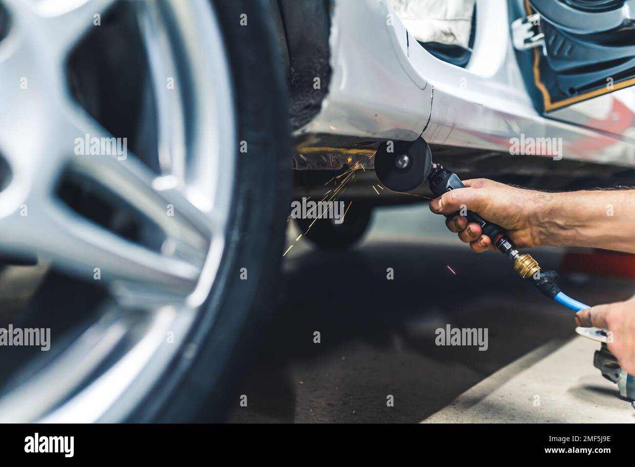 Unrecognisable man using small rotary saw tool to cut out part of body ...