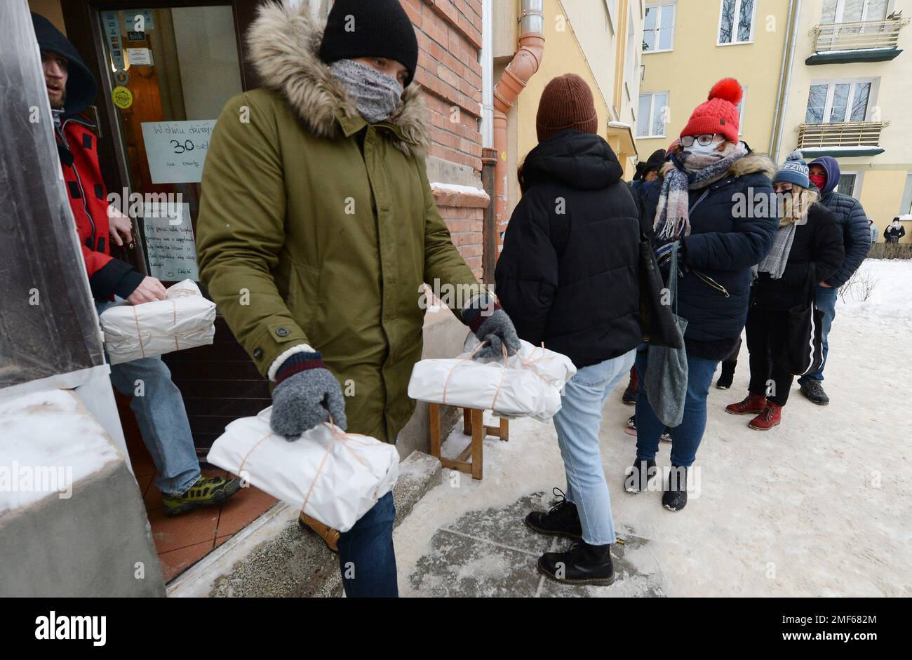 A man wearing a face mask passes a queue as he leaves a popular bakery ...