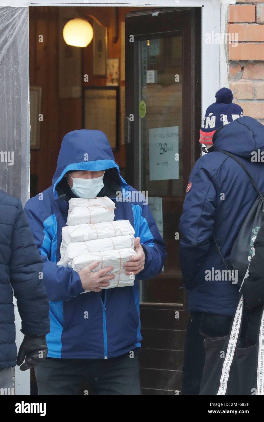 A man wearing a face mask passes a queue as he leaves a popular bakery ...