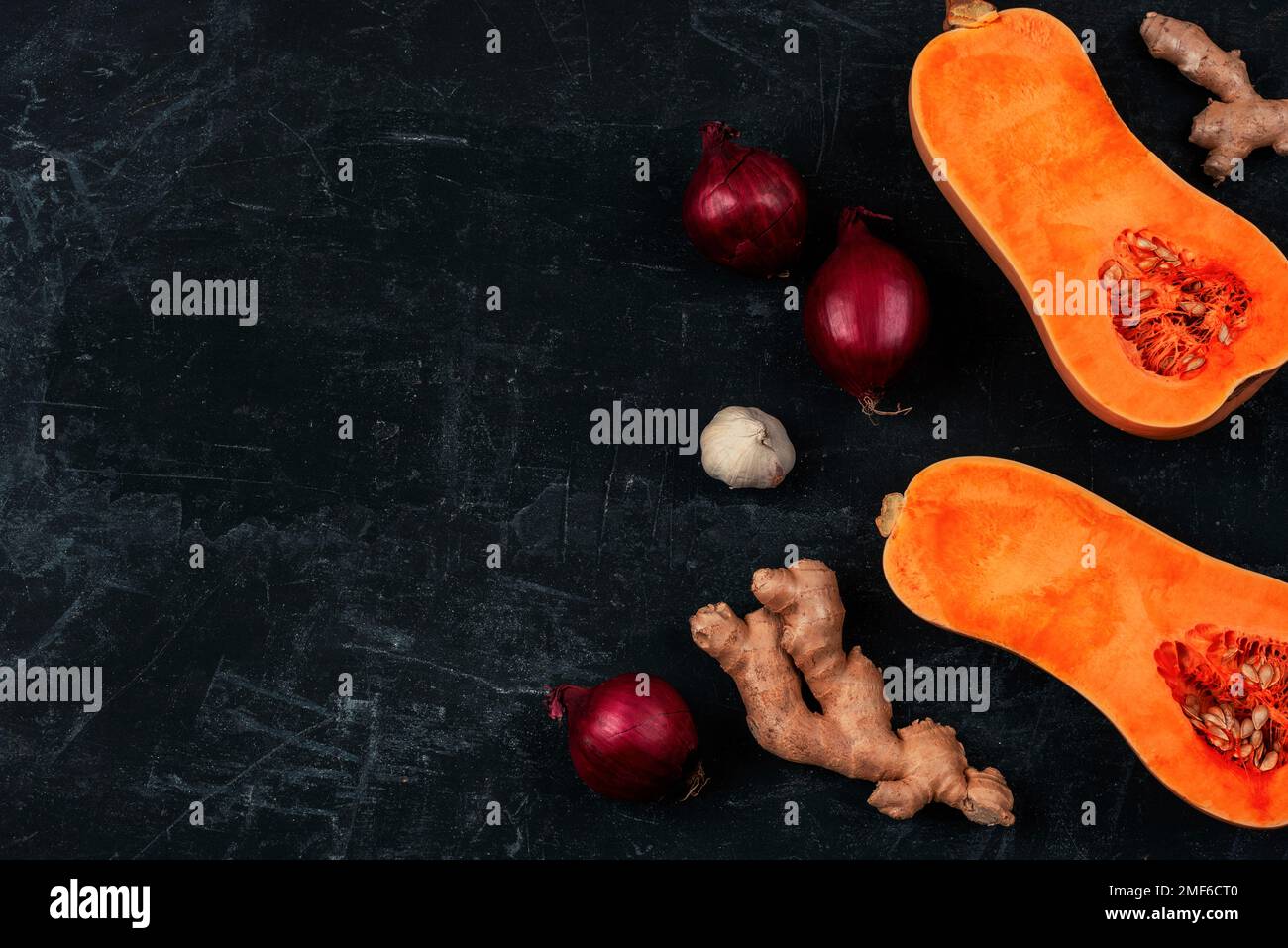 Raw butternut squash with red onion, ginger and garlic on black ...