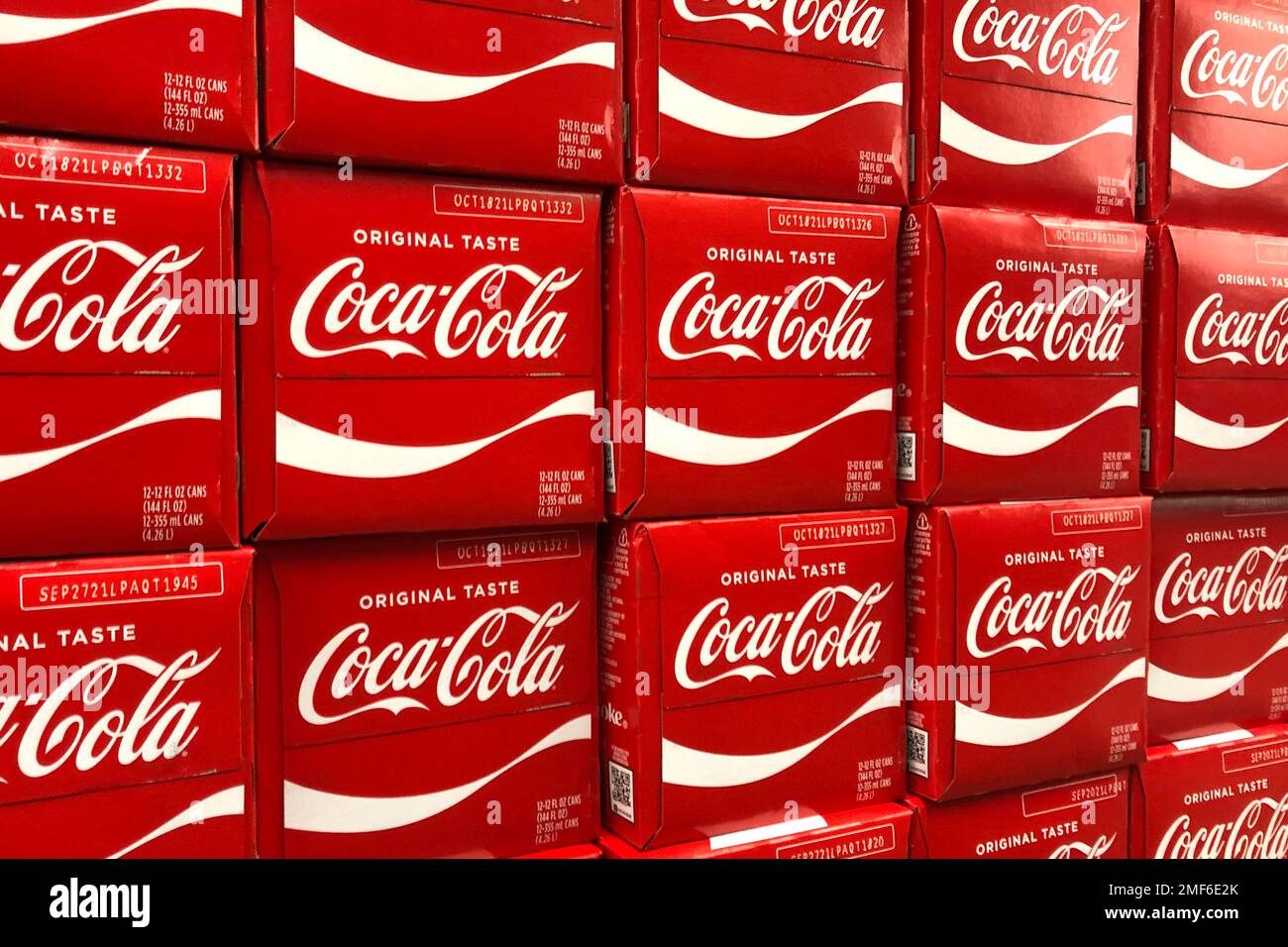 Cartons of Coca-Cola beverages are stacked on a shelf at a store ...