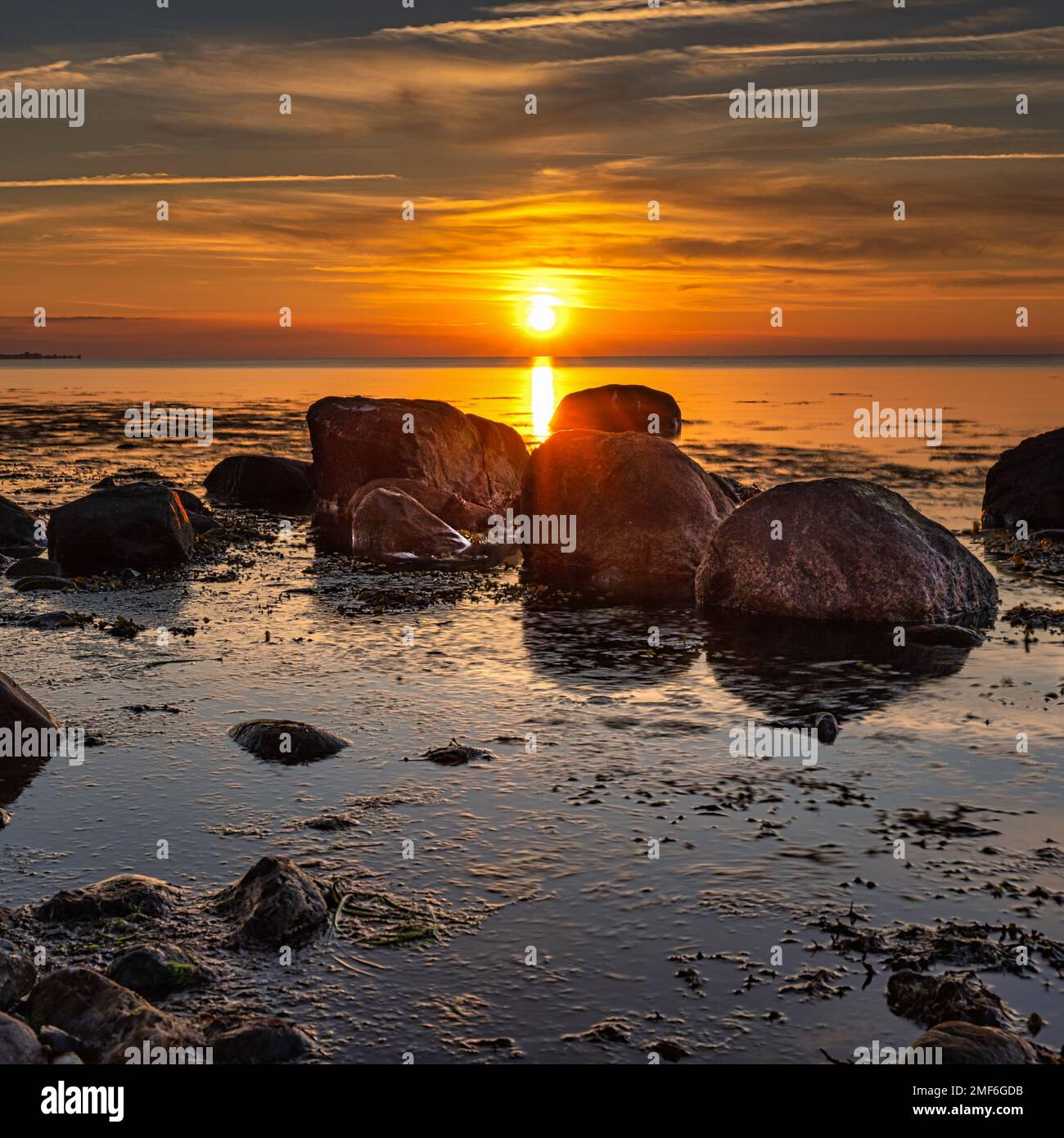 A shore full of rocks with a sea in the background during scenic sunset ...