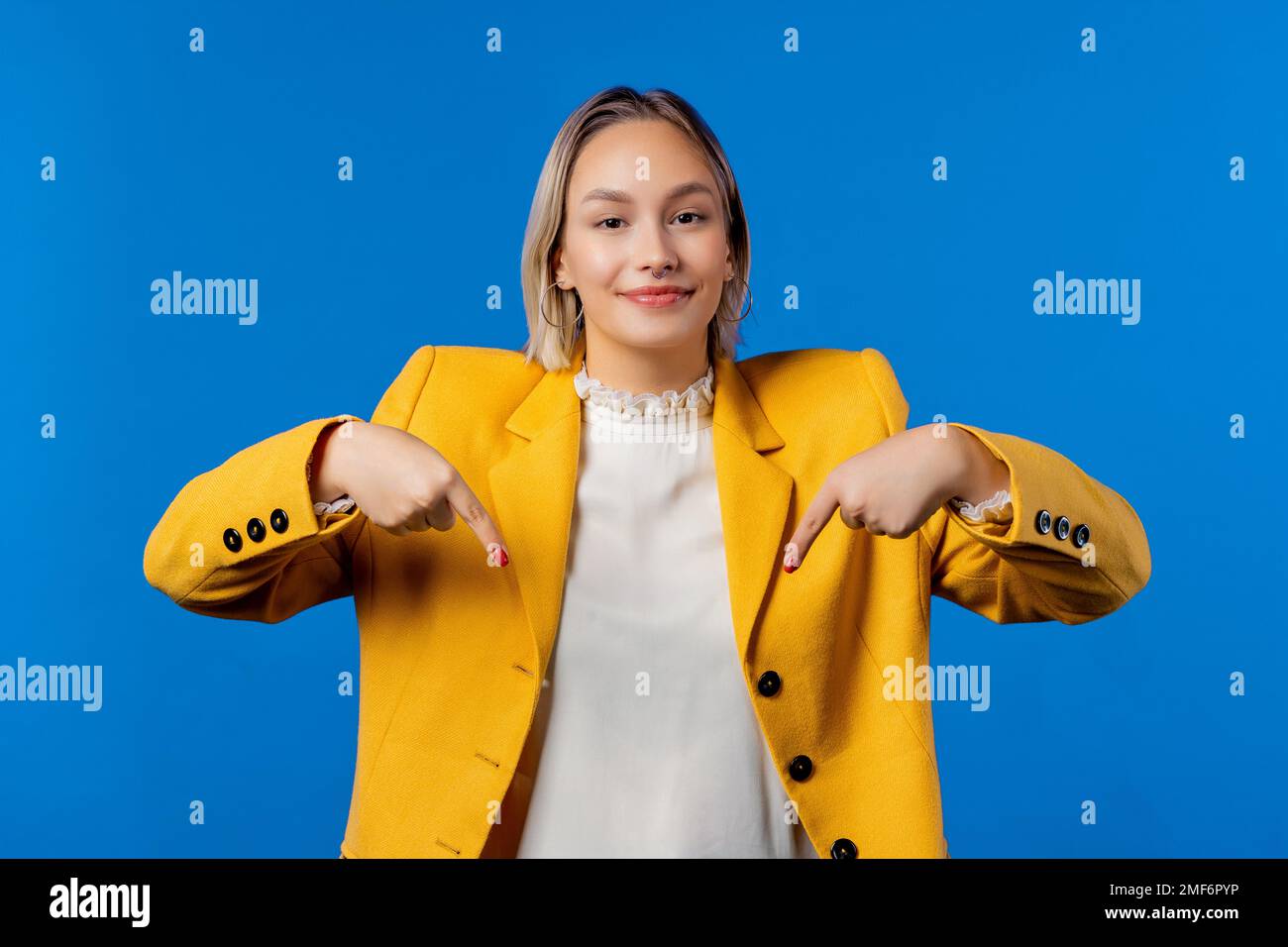 Blonde woman pointing down to advertising area. Blue background. Click ...