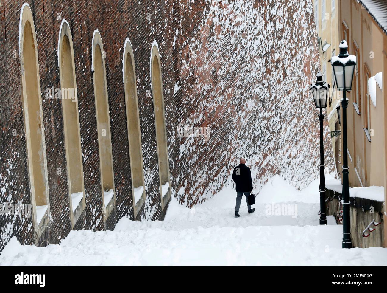 A man walks past a snow covered wall after a heavy snowfall in Prague ...