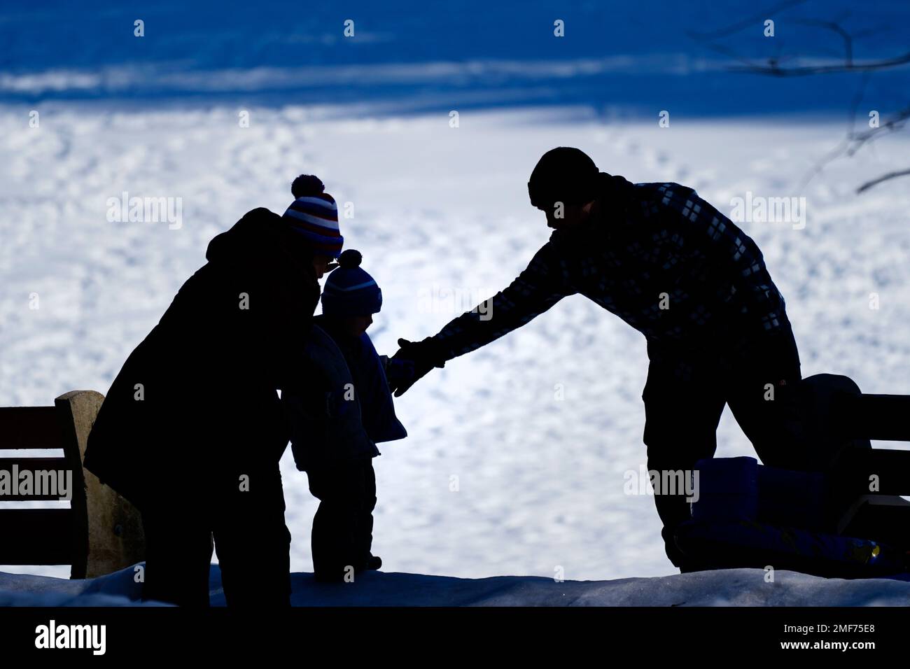 A couple helps a child on a snow covered embankment at Lorimer Park in ...