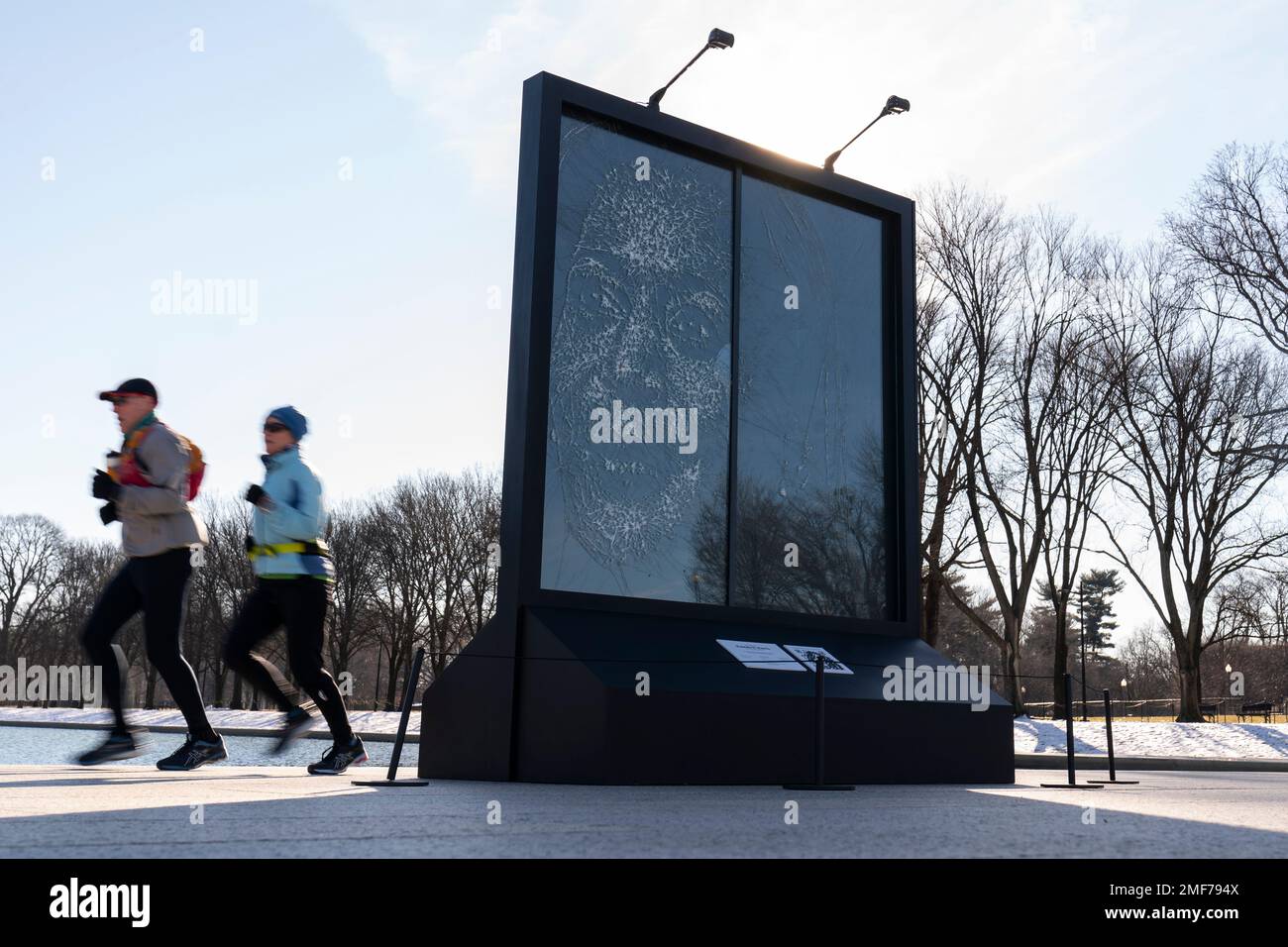 Joggers pass behind the installation "Vice President Kamala Harris ...