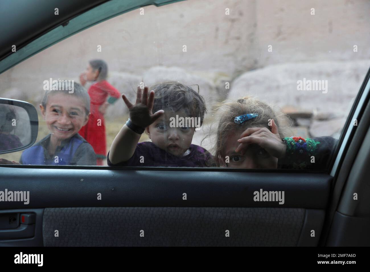 Afghan children look into a window of a car on the outskirts of ...