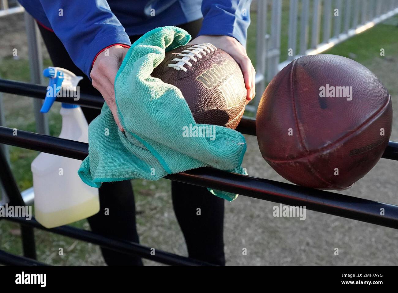 A staff worker sanitizes a football at the Super Bowl Experience ...