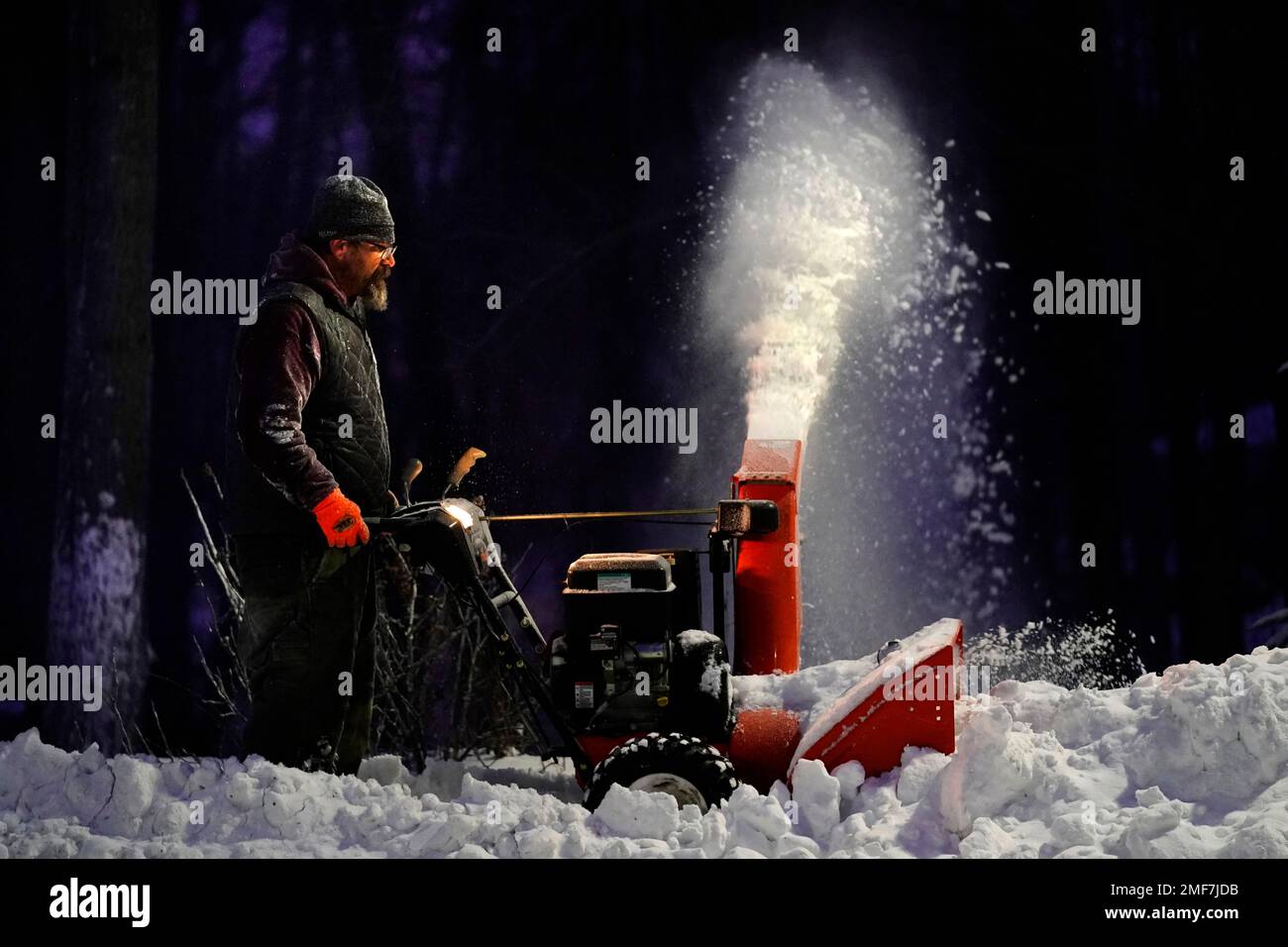 Rick Wallace clears a sidewalk with a snowblower during a winter snow ...
