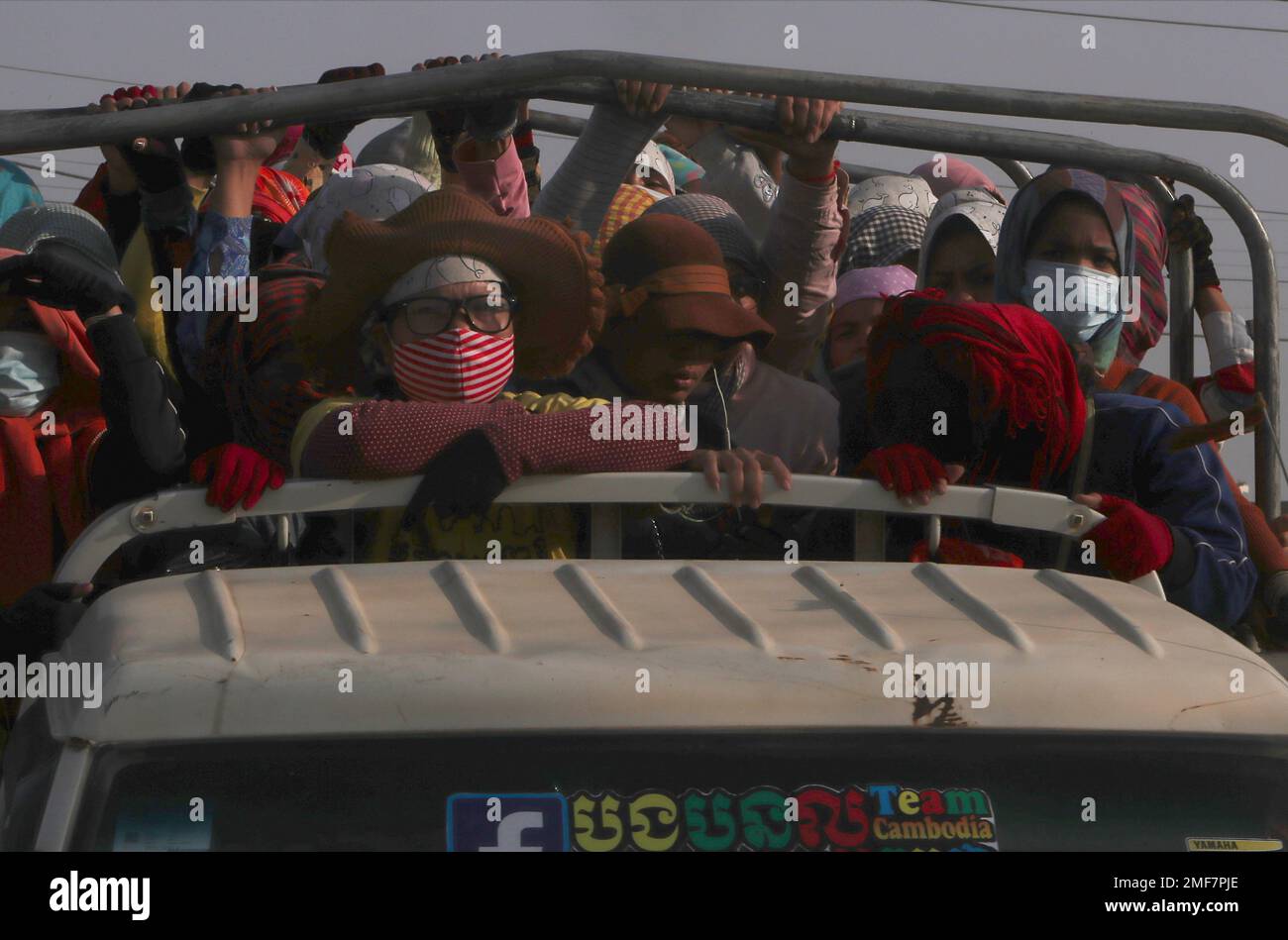 Garment workers stand on a truck as they head home after their work ...