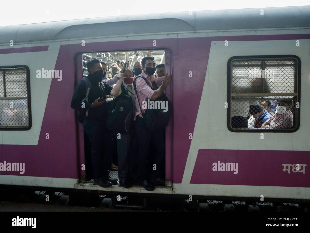 People wearing masks ride on a train as suburban train services resumed ...