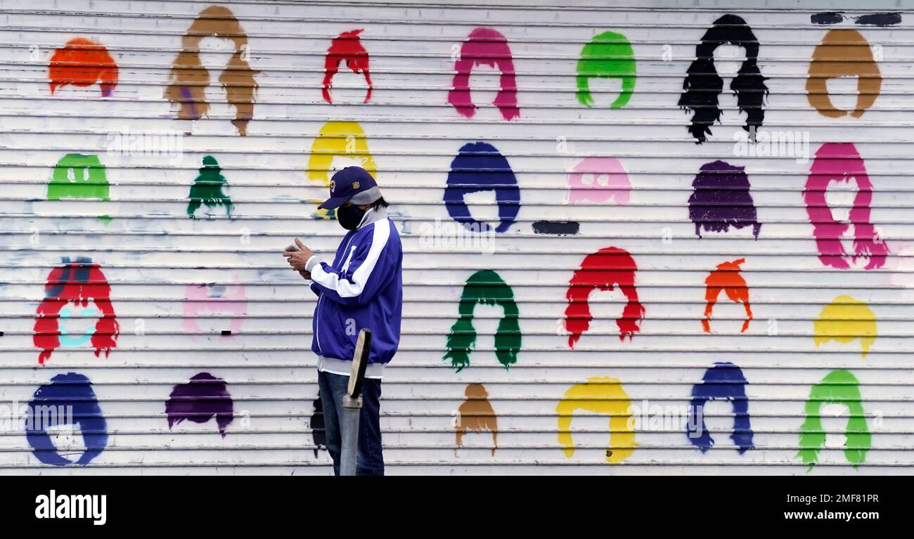A masked pedestrian checks his phone against a graphic design on a ...