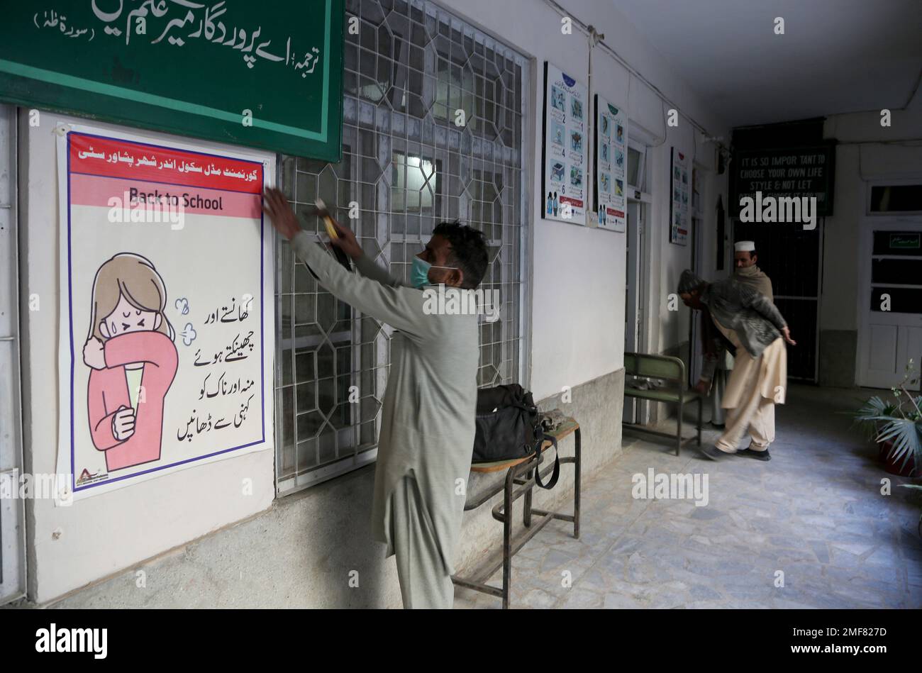 Workers fix posters informing of precautions to help prevent the spread ...