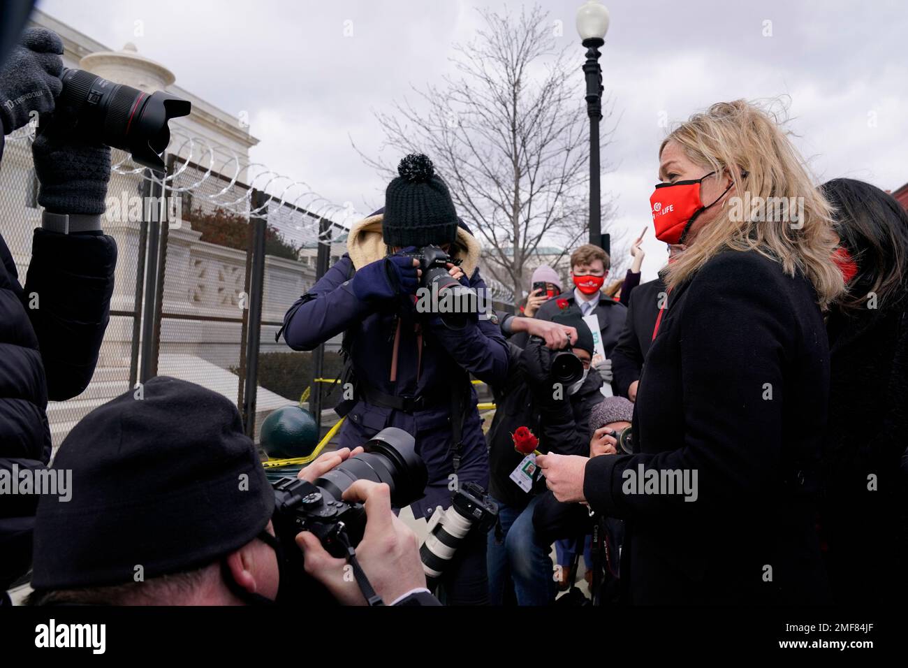 A woman is surrounded by photographers as she goes to place a rose on ...