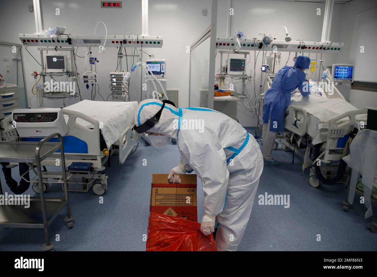 A cleaning worker collects waste in biohazard bag as a member of ...