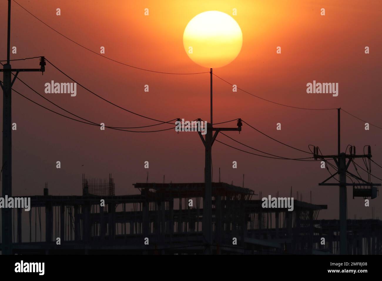 The sun sets above an electric pole near a construction site in Krang Thnung village outside ...