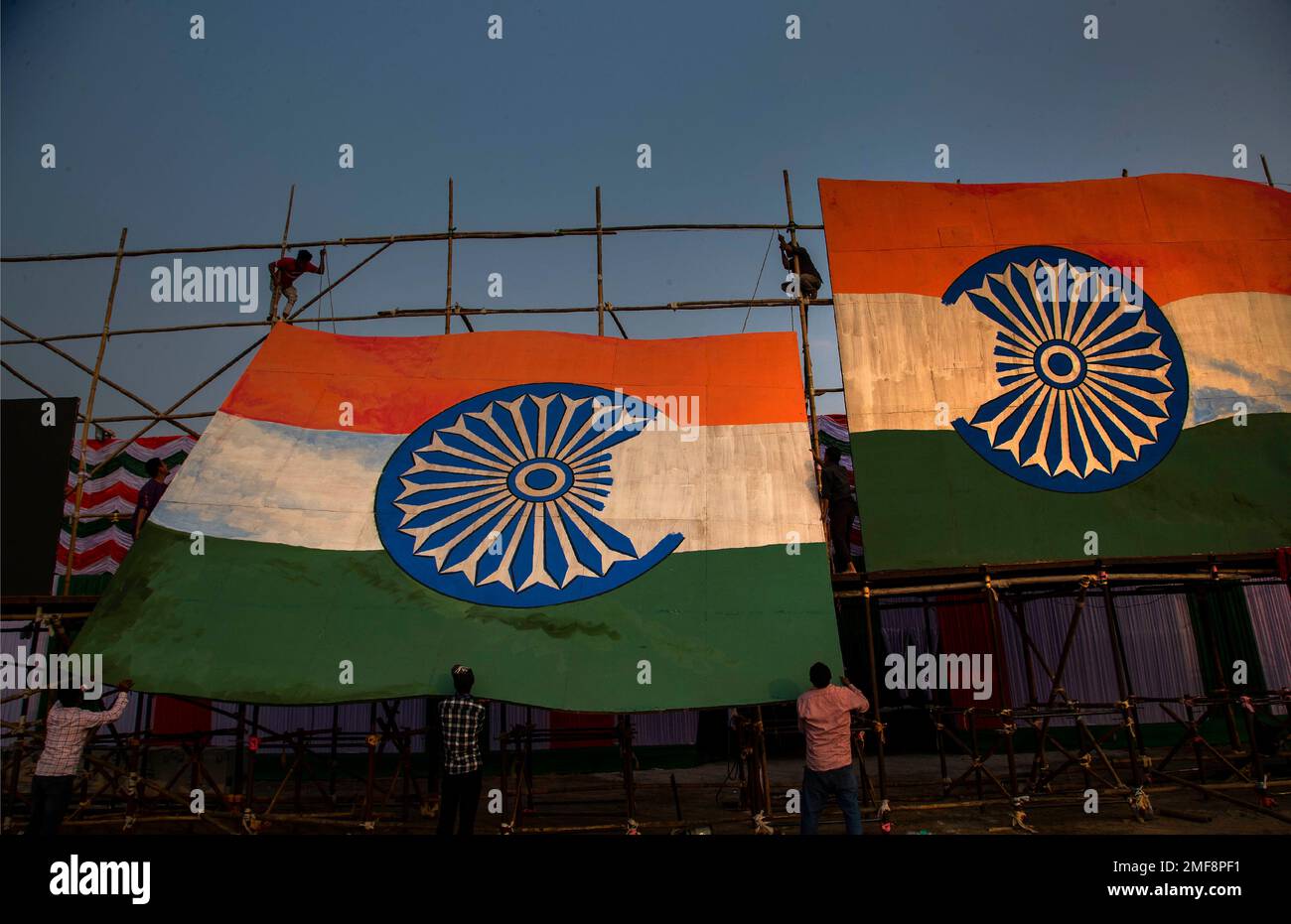 Indian workers fix a giant board painted with Indian flags at a venue ...