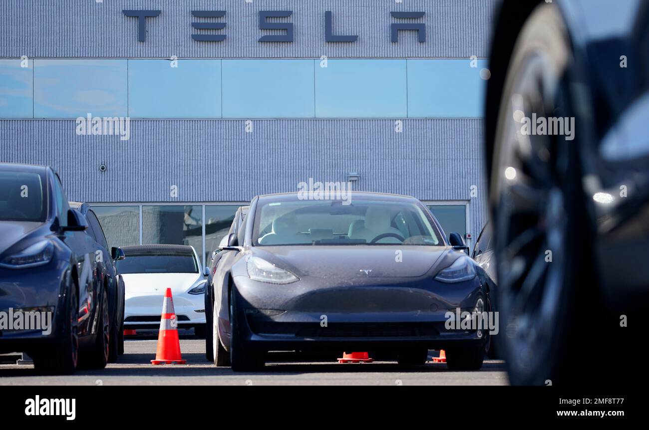 A long line of unsold 2021 Model 3 sedans sits at a Tesla dealership ...