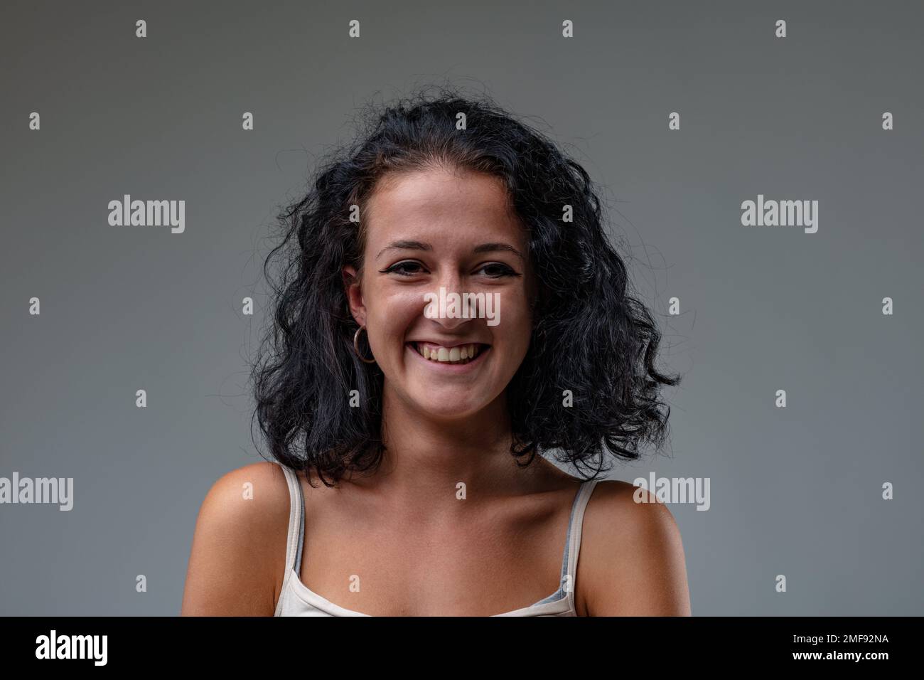 frontal portrait of a young brunette girl in a tank top laughing or ...