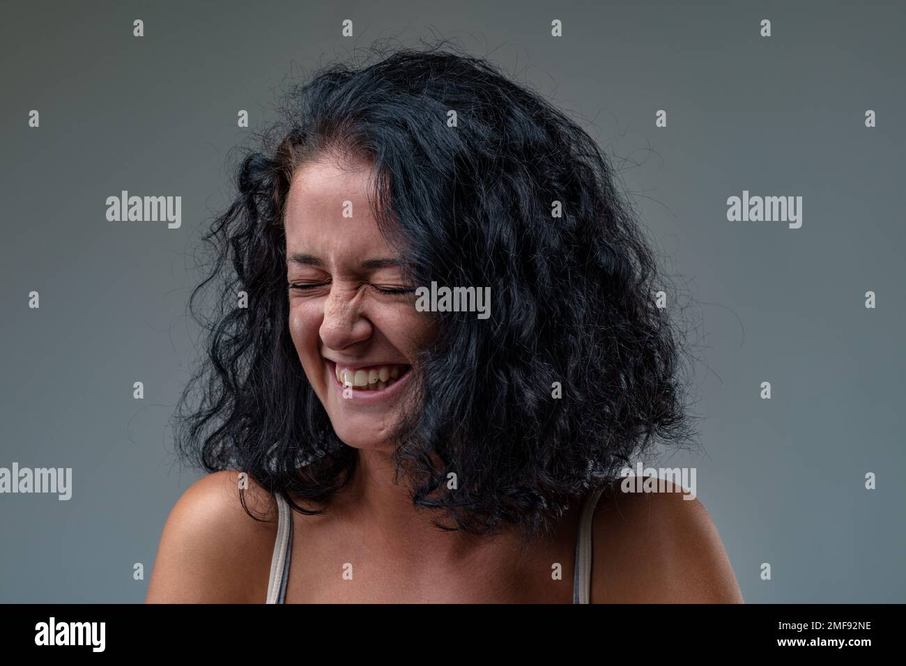 Frontal Portrait Of A Young Brunette Girl In A Tank Top Laughing Or Smiling Unable To Restrain
