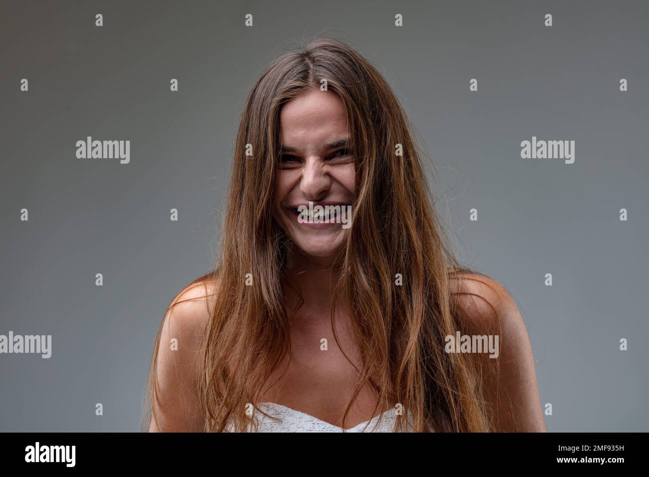 Frontal portrait of a young brown-haired girl wearing a white sheath ...
