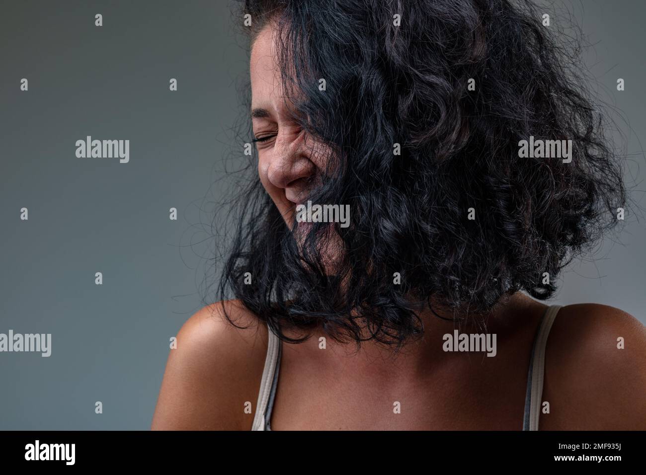 frontal portrait of a young brunette girl in a tank top laughing or ...