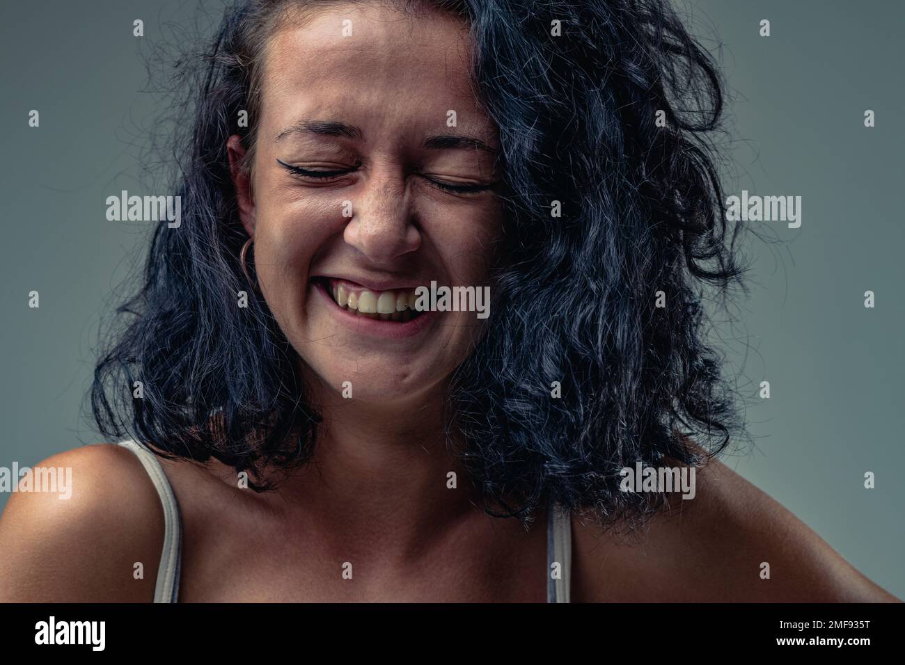 frontal portrait of a young brunette girl in a tank top laughing or ...