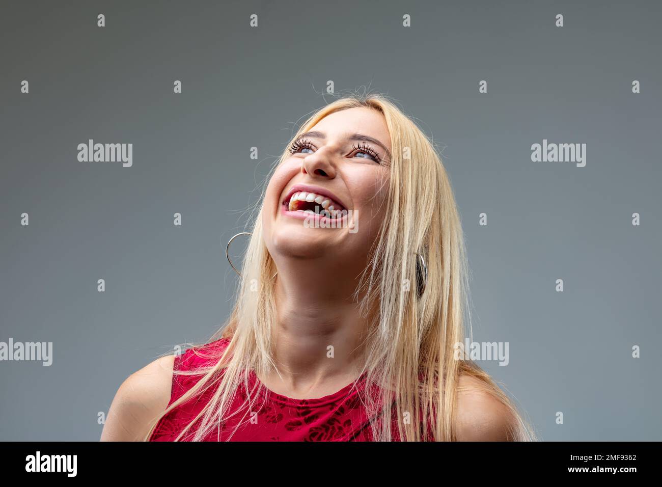 Frontal Portrait Of Young Blond Woman In Deep Red Dress Gradually