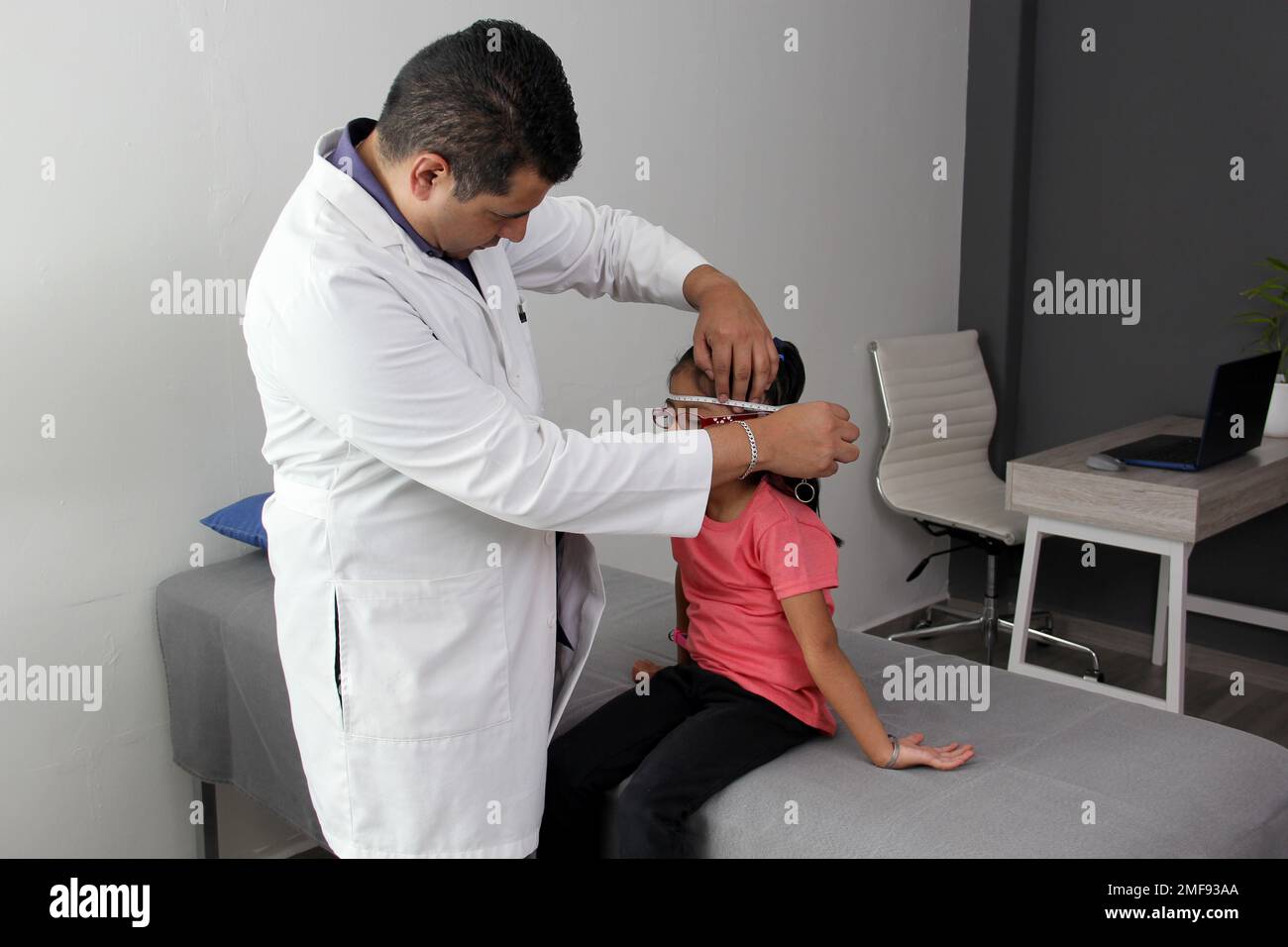 Latino pediatrician specialist doctor measures the head of his patient ...