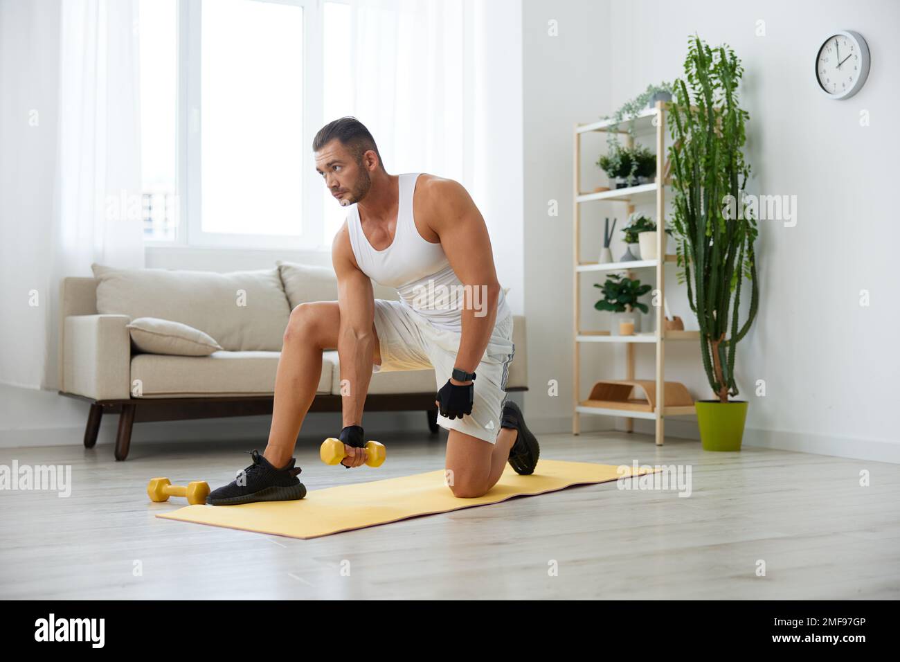 Man sports home training on the floor on a mat with dumbbells ...