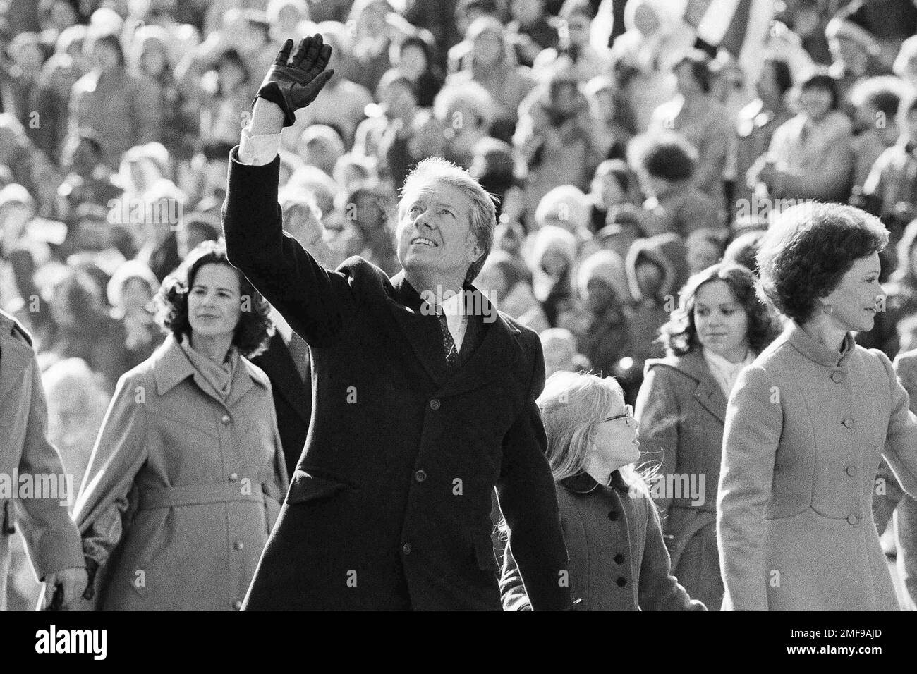 President Jimmy Carter waves to the crowd while walking with his wife ...