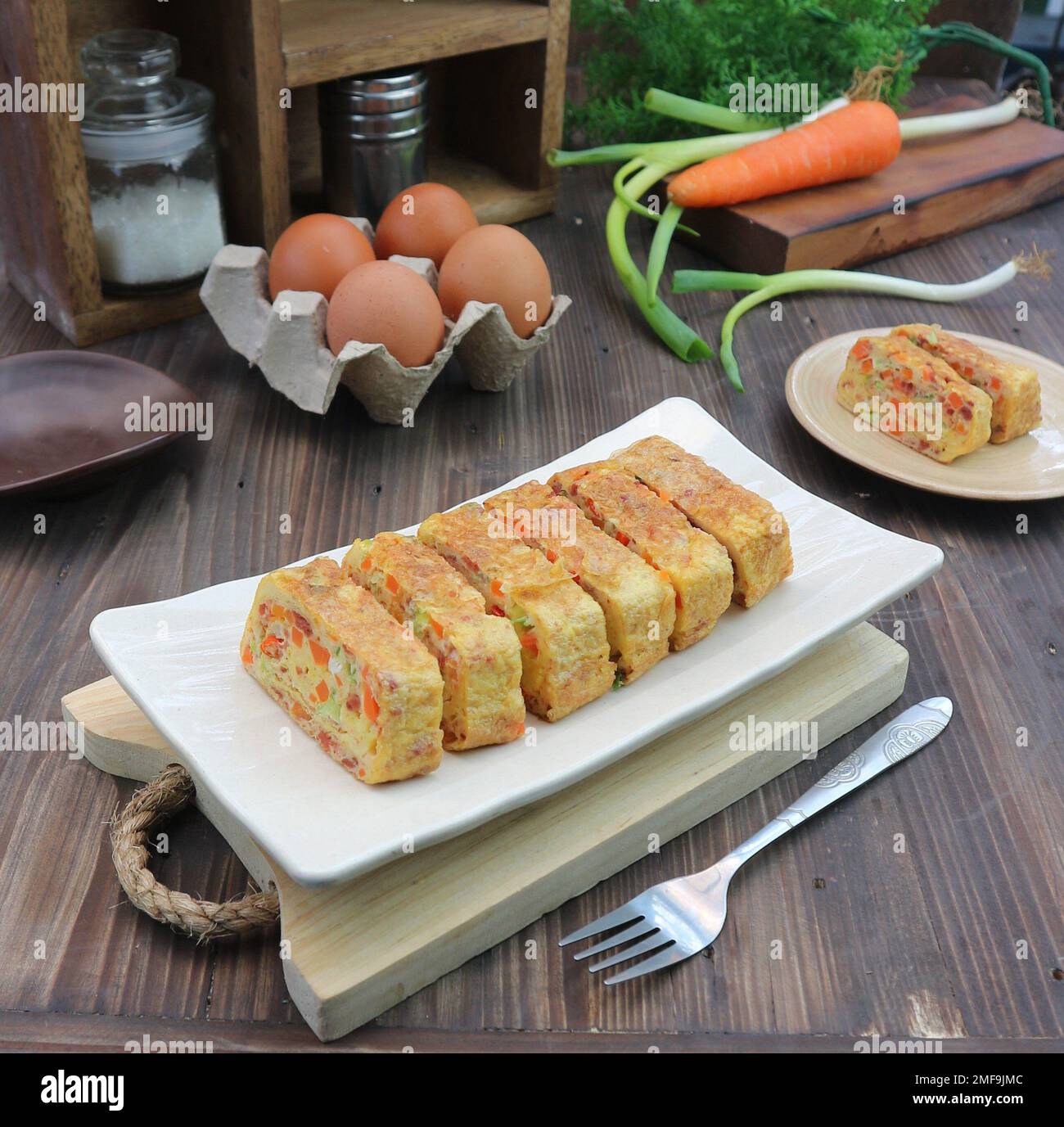 Omelette served on a white tray against a background of fresh eggs and ...