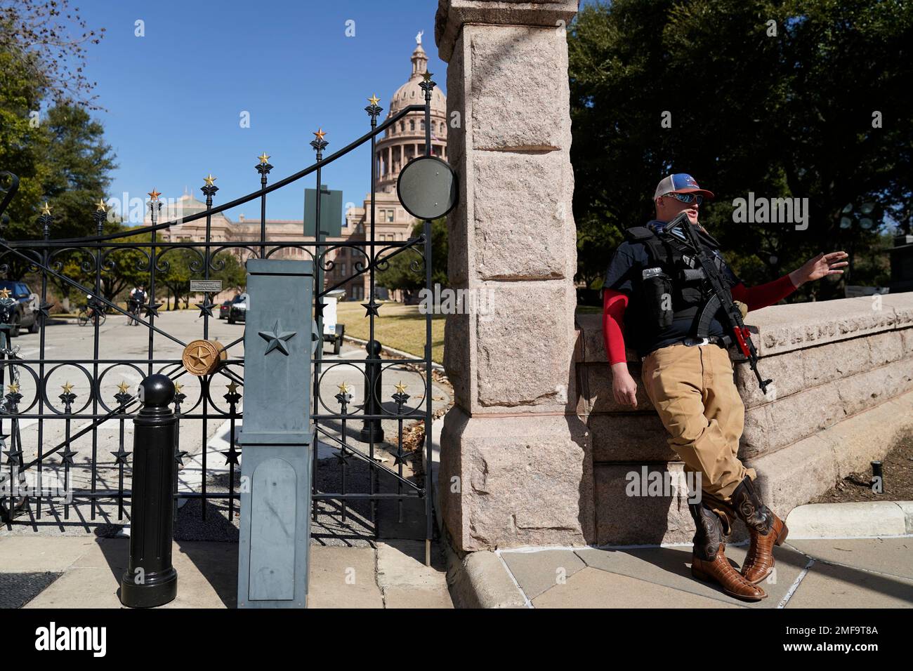 An armed demonstrator leans on a locked gate to the ground of the Texas ...