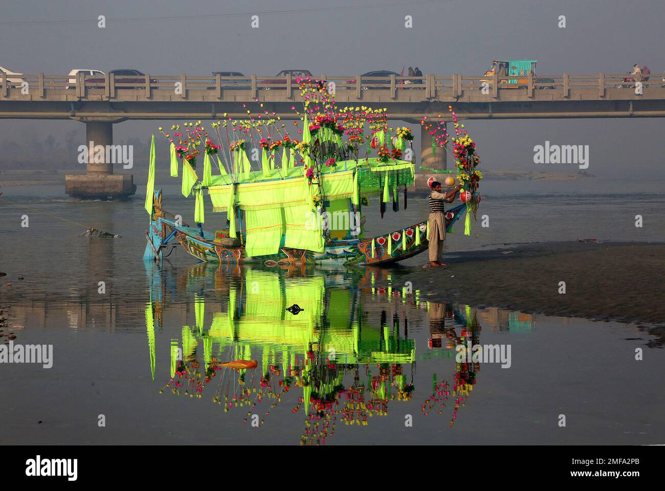 A man stands beside his decorated boat and waits for visitors during a ...
